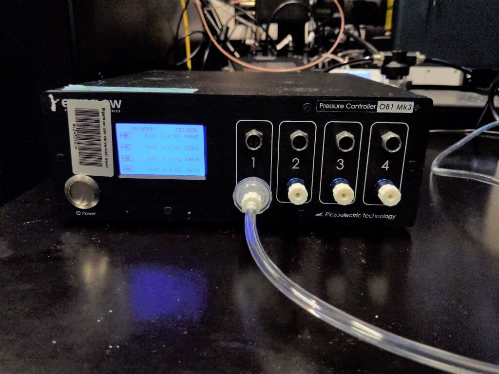 How do you synchronize a microscope with a microfluidic perfusion system?
