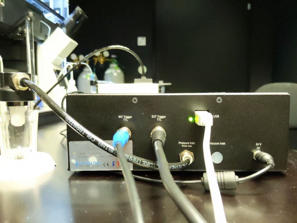 How do you synchronize a microscope with a microfluidic perfusion system?